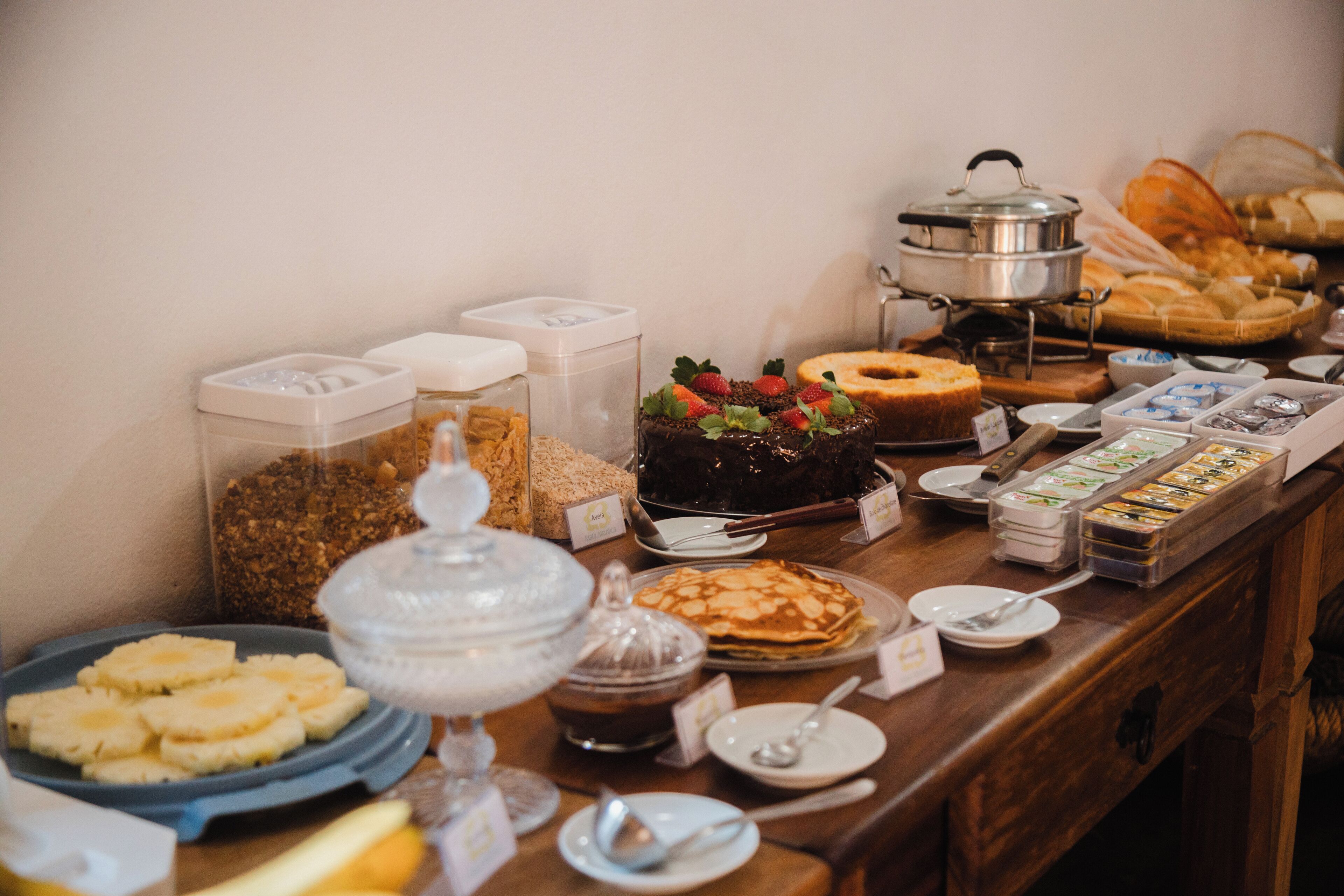 Buffet com diversos alimentos, incluindo bolo, doces e uma variedade de patês.