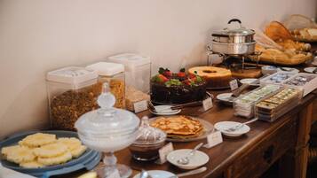 Buffet com diversos alimentos, incluindo bolo, doces e uma variedade de patês.