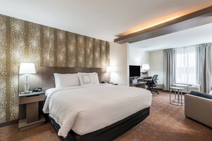 Quarto de hotel com uma cama grande, uma escrivaninha, uma cadeira e um sofá.