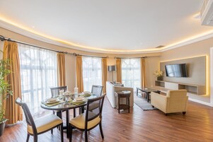 Uma sala de estar moderna com área de jantar, um sofá, uma televisão na parede e um vaso de planta.