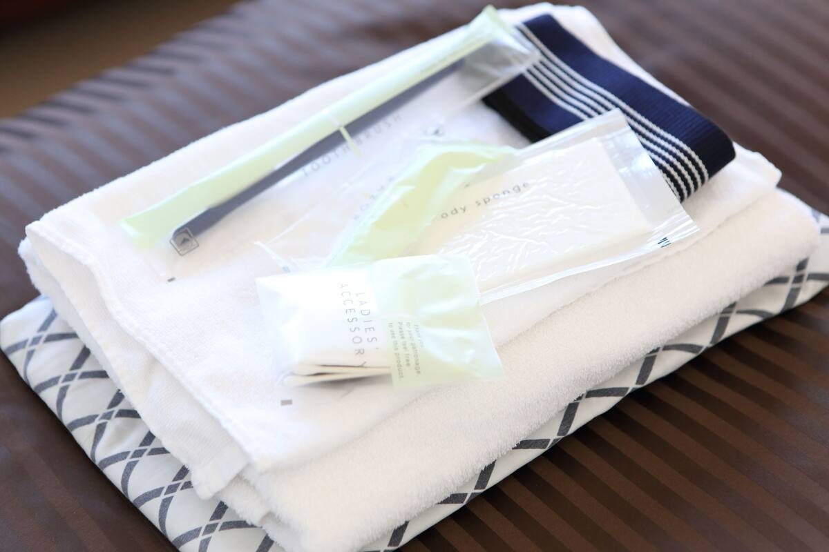 Um conjunto de artigos de higiene pessoal bem organizado, incluindo escova de dentes, esponja para o corpo e um pequeno sachê, sobre uma almofada estampada.