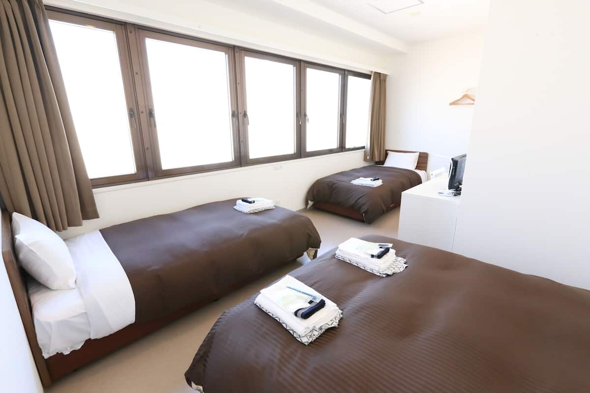 Quarto de hotel com duas camas de solteiro, uma escrivaninha e uma televisão.