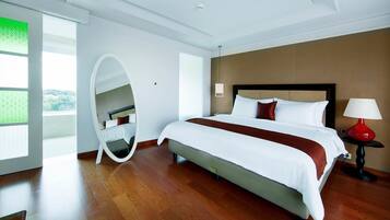 Quarto de hotel com uma cama grande, um espaço de estar com espelho e vista para o exterior.