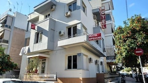 Um hotel com várias andares, varandas, aparelhos de ar condicionado e uma placa indicando que é um hotel.