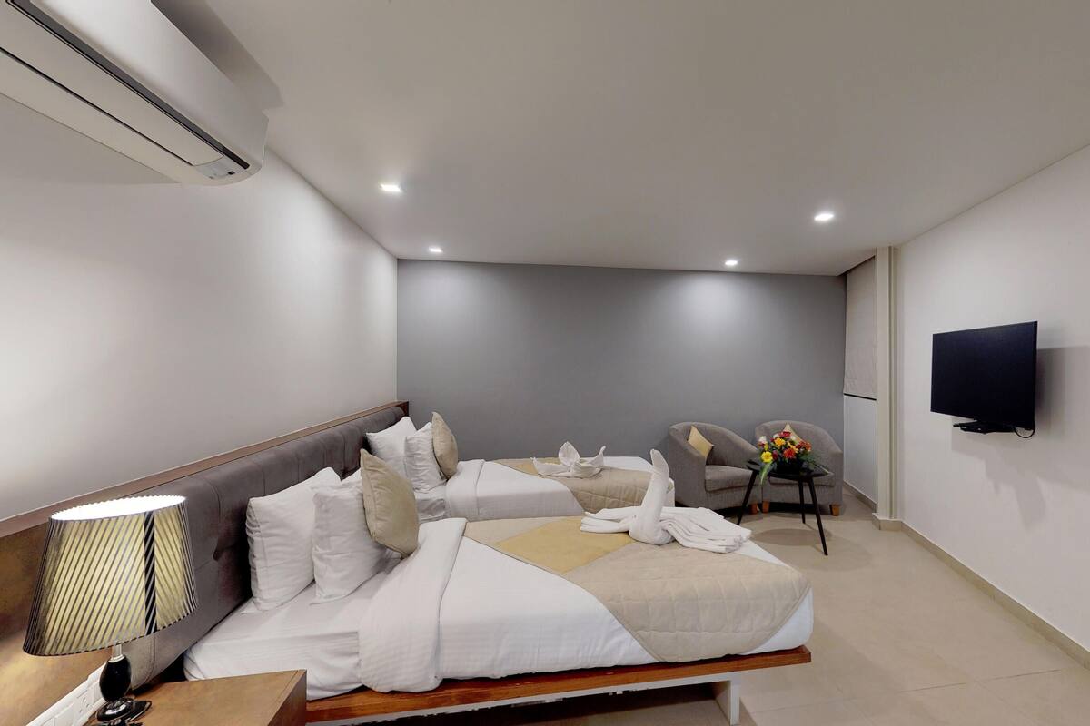 Quarto de hotel com uma cama, uma cadeira, uma televisão e um abajur.