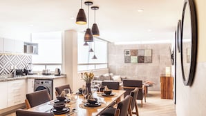 Cozinha moderna com área de jantar, apresentando uma mesa de madeira, cadeiras e iluminação pendente.