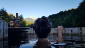Uma pessoa em uma piscina com duas garrafas de cerveja em um pedestal.