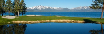 Um campo de golfe tranquilo com vista clara para montanhas cobertas de neve ao fundo.