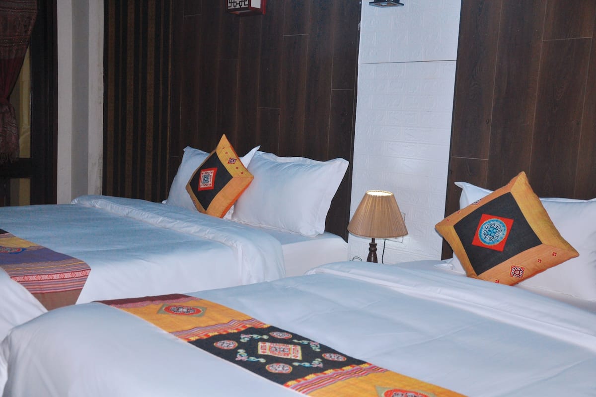 Quarto de hotel com duas camas, cada uma com colcha estampada e almofadas decorativas.
