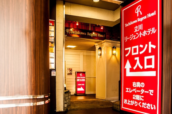 Entrada do Hotel Tachikawa Regent com uma placa indicando a direção para a entrada principal.