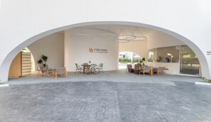 Uma área de estar ao ar livre espaçosa, com mobiliário moderno e vista desimpedida para a piscina ao fundo.