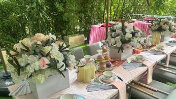 Mesa posta com centros de mesa florais, suporte escalonado para cupcakes e um jarro de vidro.