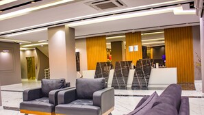 Um lobby moderno com balcão de recepção, área de estar e piso de mármore.