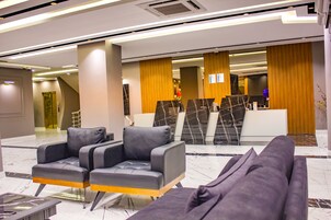 Um lobby moderno com balcão de recepção, área de estar e piso de mármore.