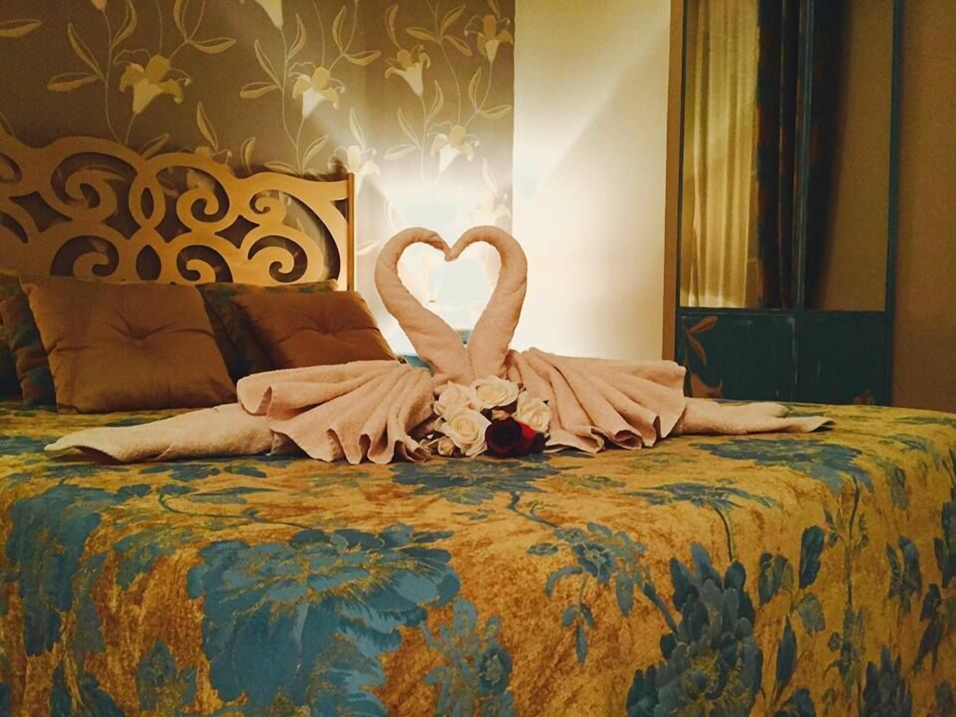 Cama com colcha florida e cabeceira decorativa.