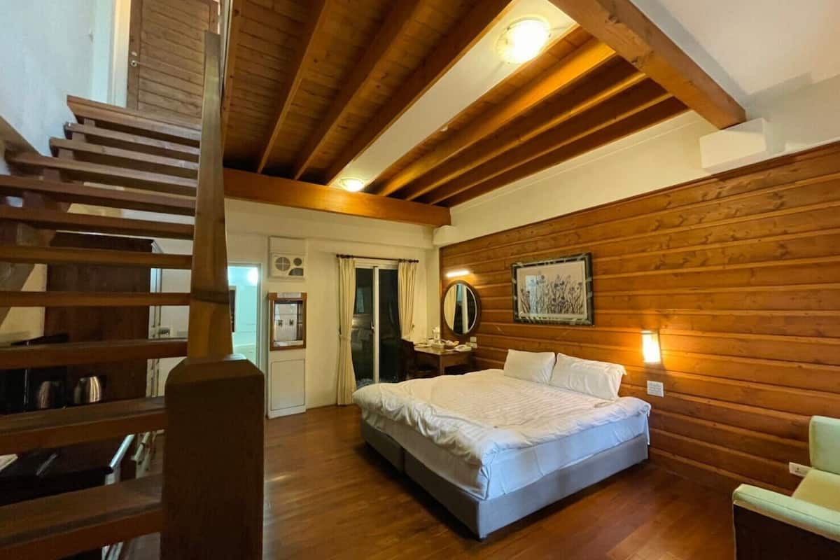 Quarto com teto de madeira, cama, escrivaninha e cadeira.