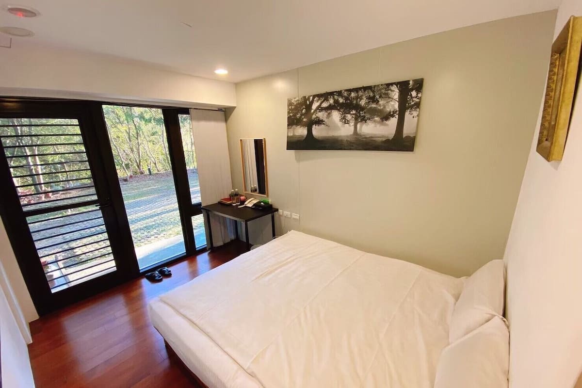 Quarto com cama grande, escrivaninha com espelho e pintura na parede.