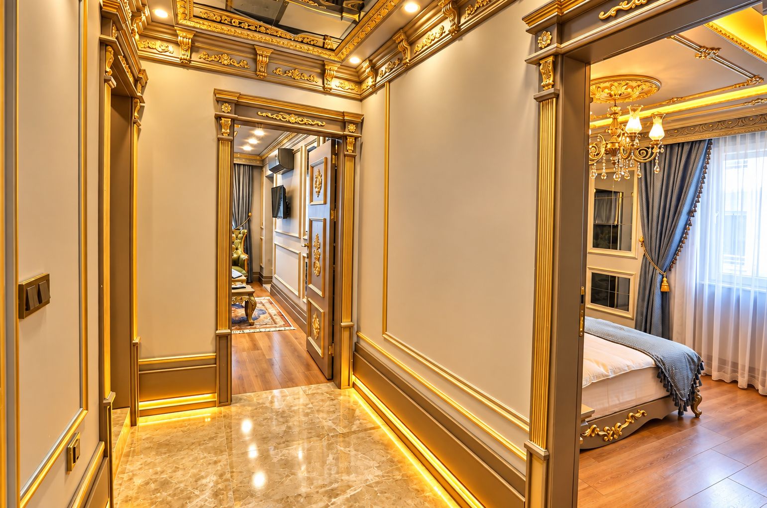 Um corredor luxuoso com detalhes dourados elaborados e piso de mármore, que leva a um quarto com cama e cortinas.