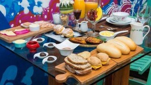 Um buffet de café da manhã com diversos alimentos e bebidas em uma mesa de vidro.