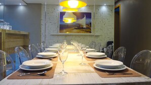 Uma mesa de jantar posta com pratos, copos e talheres, com um quadro na parede ao fundo.