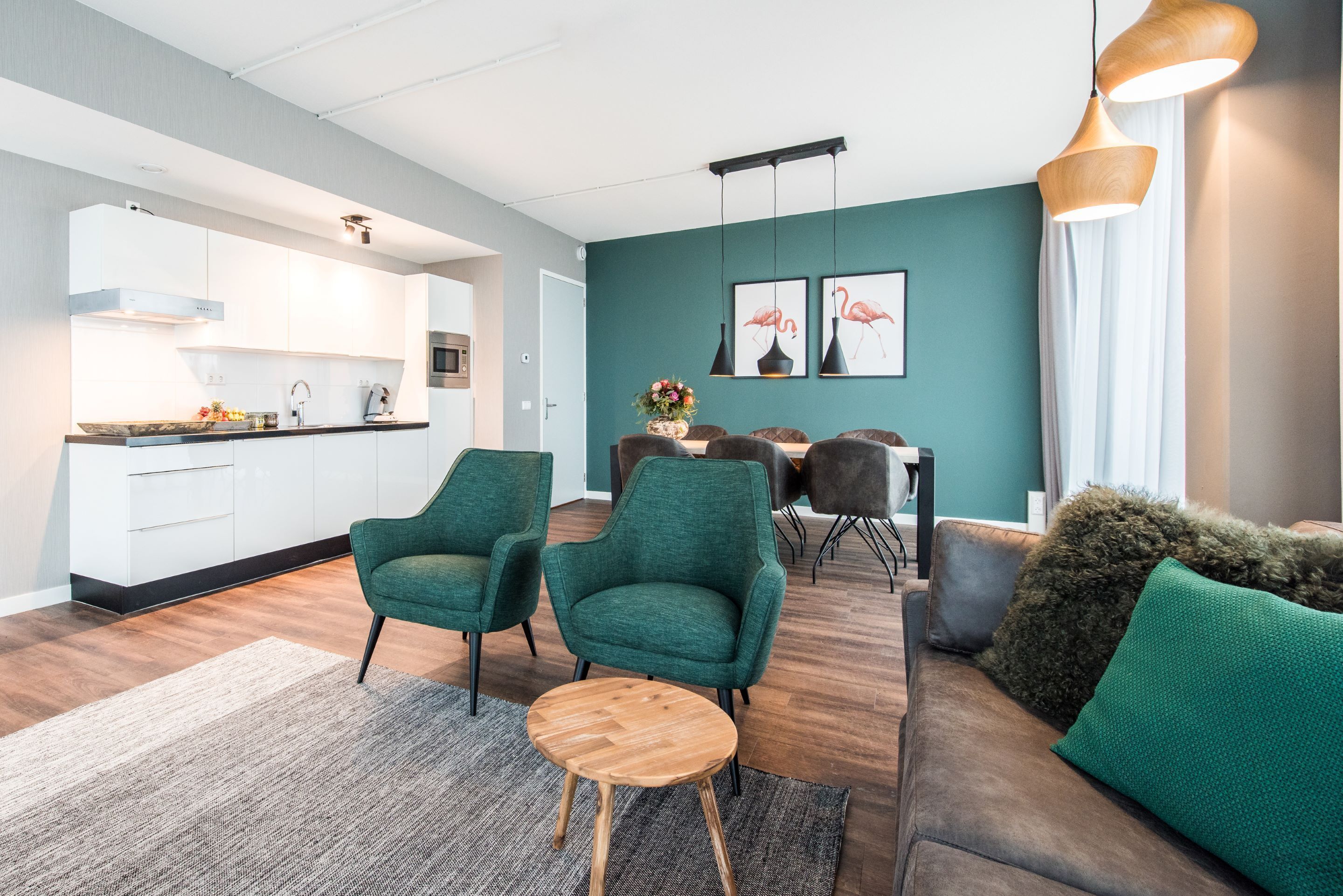 Uma sala de estar moderna com um sofá, duas poltronas, uma mesa de centro e um espaço de jantar com uma mesa e cadeiras.