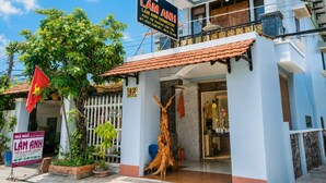 Um edifício de dois andares com uma placa indicando 'LAM ANH HOAMESTAY' e uma bandeira.