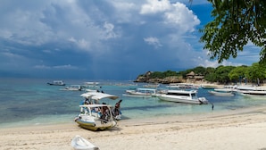 Uma praia com barcos atracados e um edifício ao fundo.