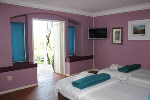 Quarto com duas camas, televisão e janela com vista para o exterior.