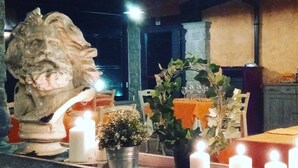 Uma estátua de pedra de um leão, um vaso de planta e várias velas acesas sobre uma mesa.