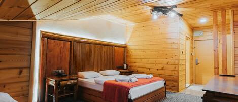Quarto de cabana de madeira com cama, mesa de cabeceira e criado-mudo.