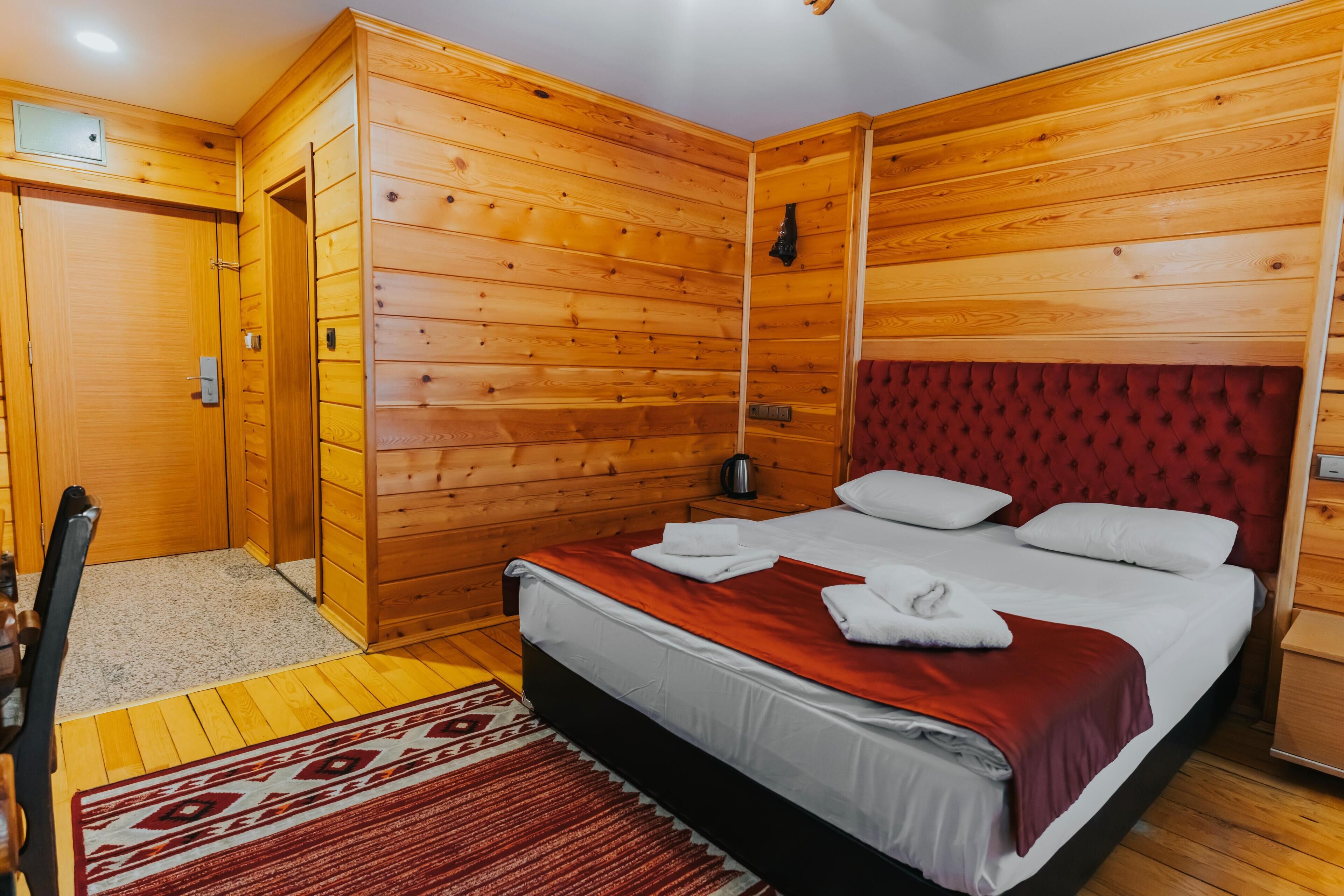 Um quarto com painéis de madeira, uma cama, uma cadeira e uma pequena mesa.