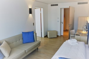 Quarto de hotel com cama, sofá, escrivaninha e cadeira.