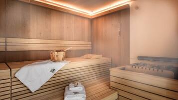 Uma sauna com bancos de madeira, um balde de madeira e toalhas.