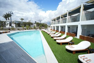Uma área junto à piscina com espreguiçadeiras e piscina.