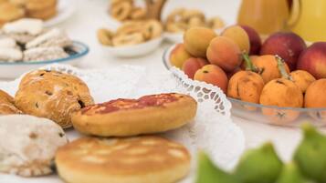 Diversos produtos de panificação e frutas frescas sobre uma mesa.