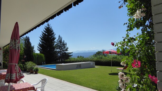 Área de pátio com piscina, mobiliário externo e vista para montanhas.