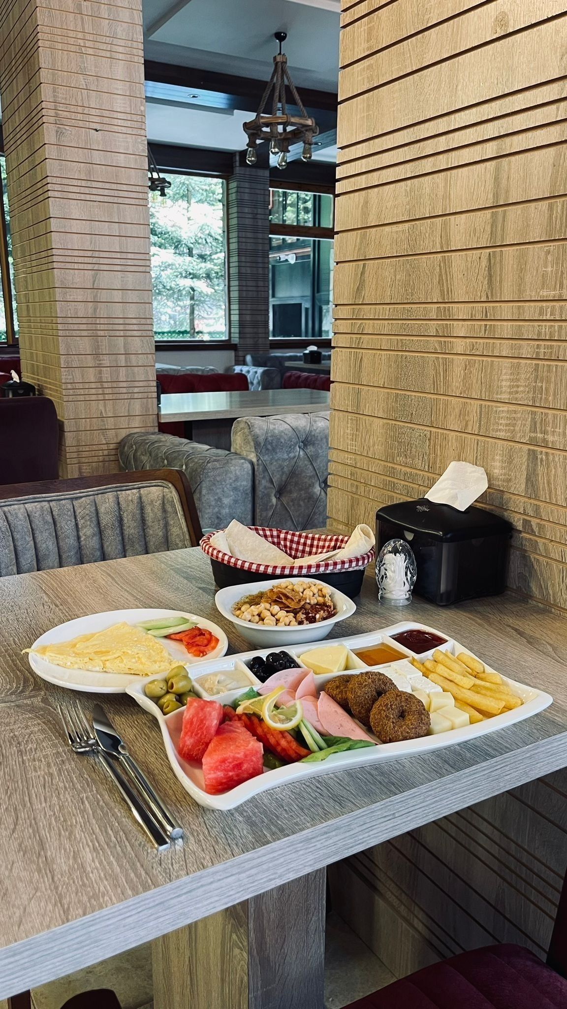 Uma mesa de jantar com diversos alimentos, incluindo um prato de ovos, vegetais e carne, e uma tigela de nozes.