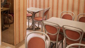 Uma sala de jantar com papel de parede listrado, uma obra de arte emoldurada e várias mesas e cadeiras.