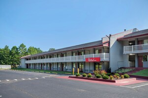 Um Red Roof Inn com estrutura de dois andares, área de estacionamento coberta e um jardim frontal ajardinado.