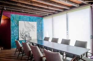Uma sala de conferências com uma mesa comprida, seis cadeiras e uma grande pintura abstrata na parede.