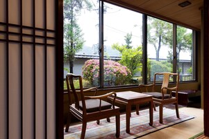 Um quarto japonês tradicional com tatames, uma mesa baixa e quatro cadeiras de madeira.