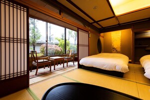 Quarto japonês tradicional com tatames, cama, escrivaninha e cadeiras.