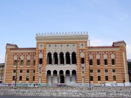 Um edifício grande e histórico com fachada simétrica, múltiplas arcadas e elementos decorativos típicos da arquitetura tradicional.
