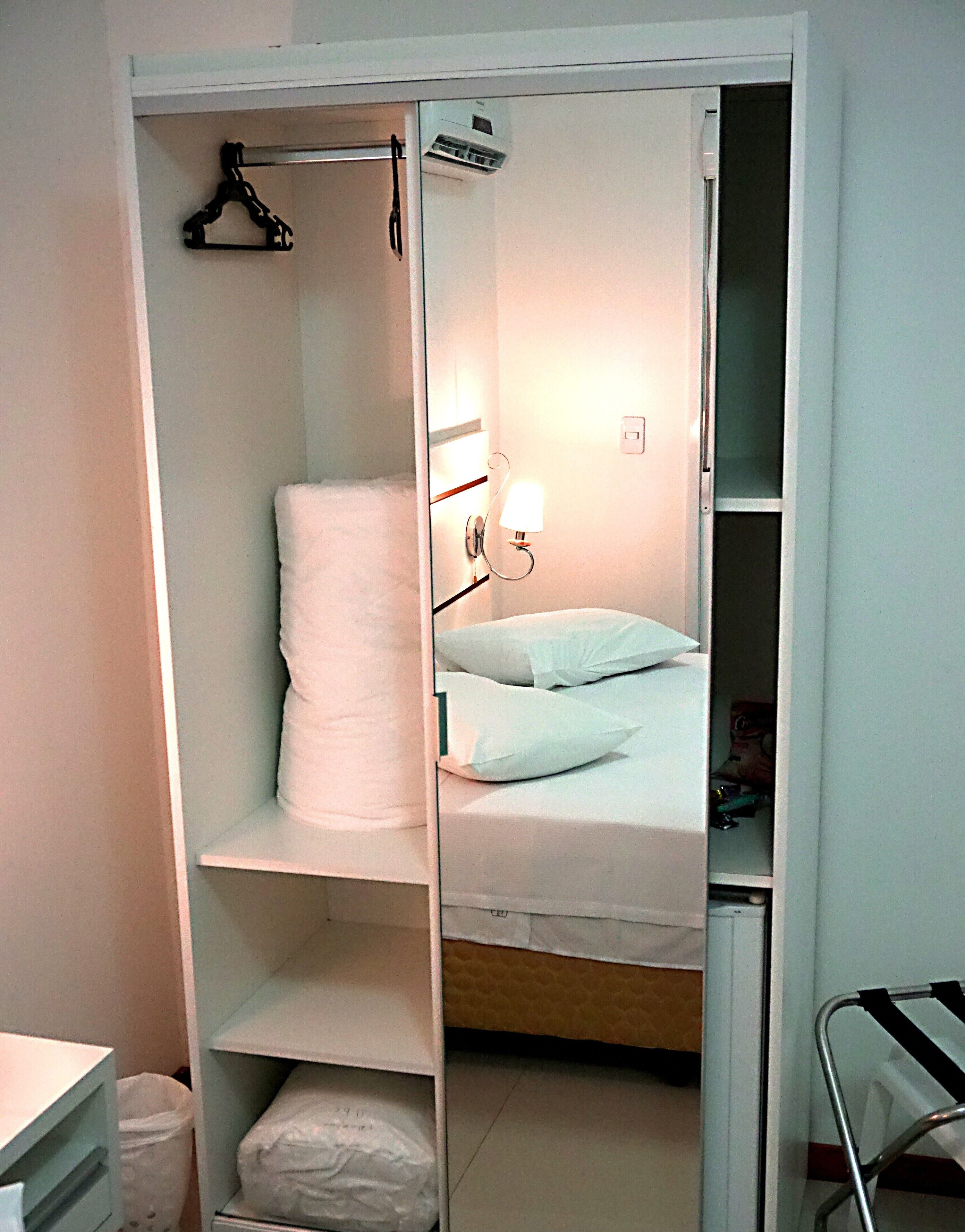 Quarto com cama, armário e estante.