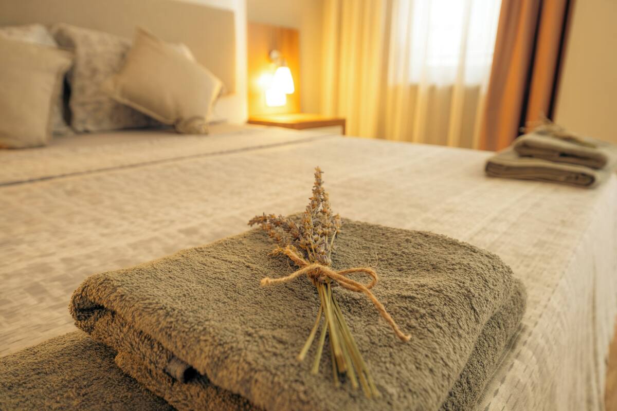 Cama bem arrumada com toalha e uma pequena planta.