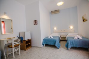 Quarto de hotel com duas camas, uma escrivaninha, uma cadeira e uma televisão.