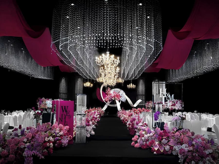 Espaço para casamento com um corredor central, decoração floral e um candelabro.
