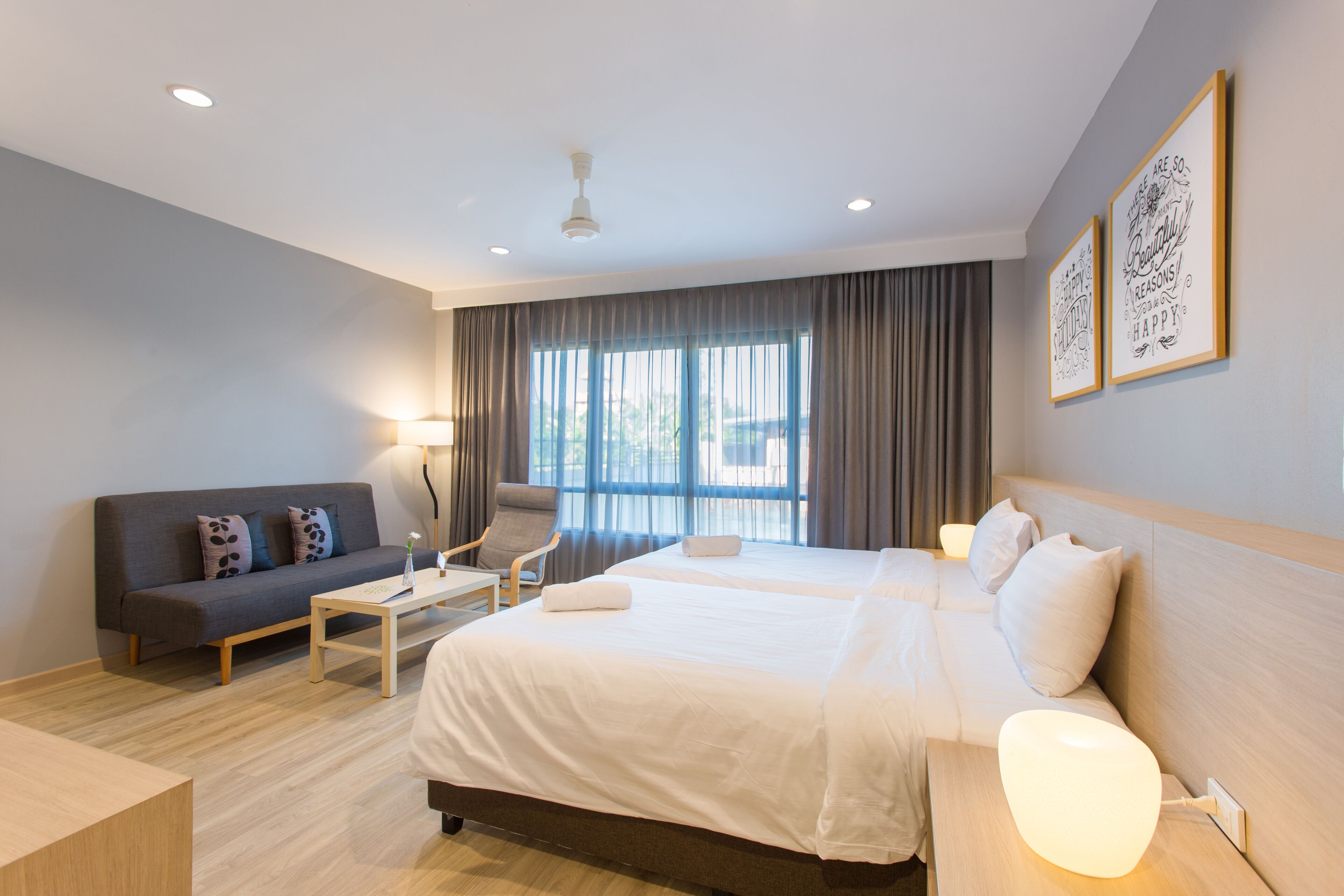 Quarto de hotel com uma cama grande, um sofá, uma escrivaninha e uma janela com cortinas.