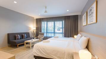 Quarto de hotel com uma cama grande, um sofá, uma escrivaninha e uma janela com cortinas.