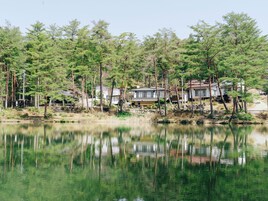Um imóvel à beira do lago com várias cabanas rodeadas por densos pinheiros.